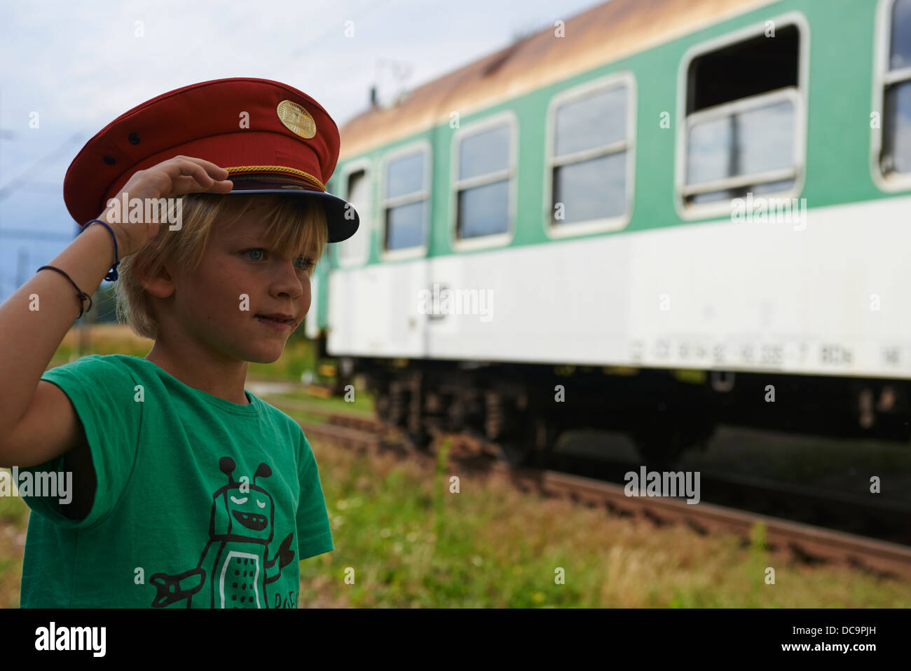 Child blond Boy with Train Dispatcher`s Cap playing in railway station ...