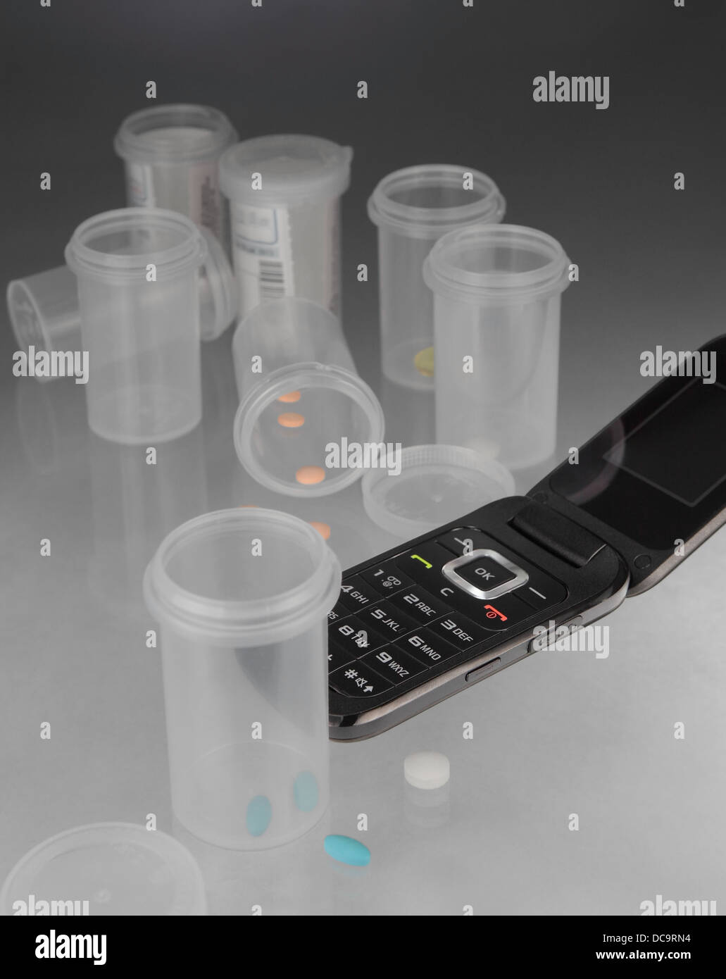 on a surface we see spilled pills and pill containers. A mobile phone ...