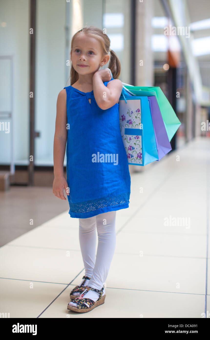 Little fashion girl with packages in large shopping center Stock Photo ...