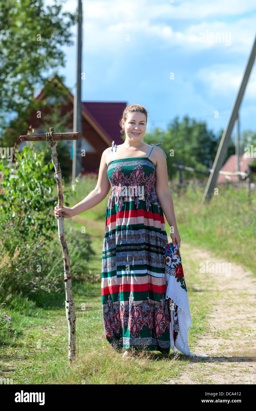 Countrywoman in village standing on rural road with working instruments ...