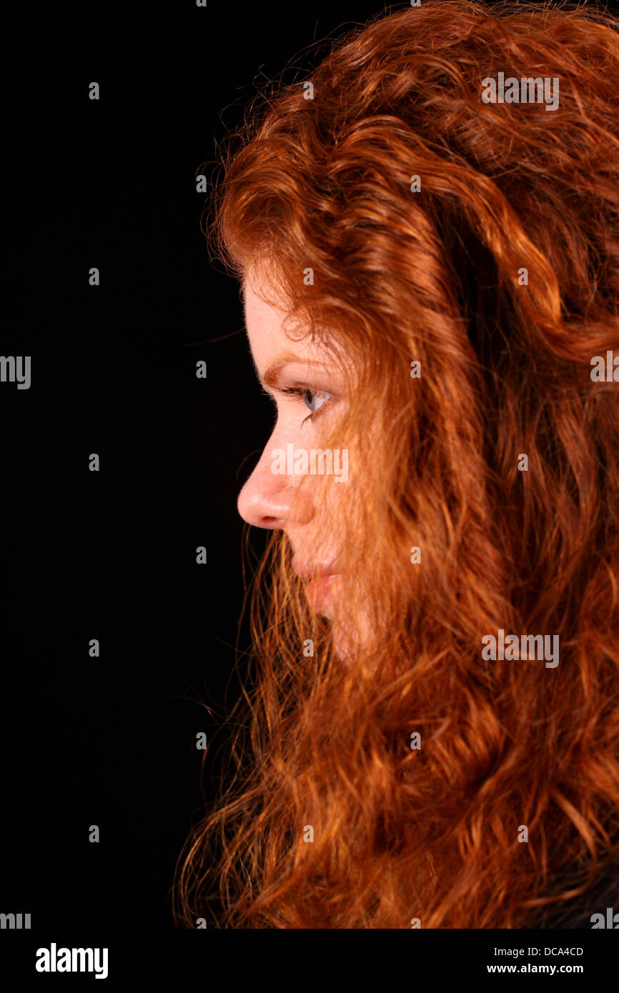 side portrait of a redheaded woman against a black background Stock ...