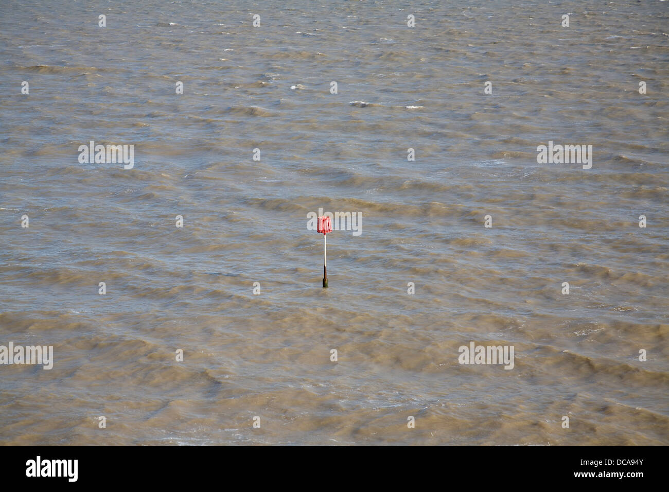 Orange groyne marker stands in choppy brown sea at high tide Stock ...