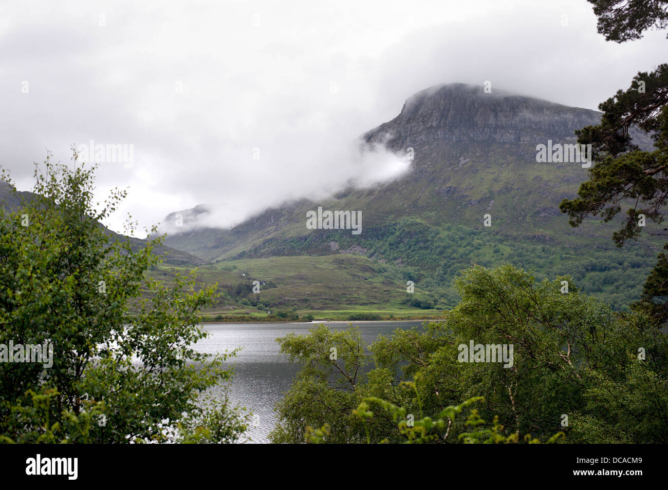 View of Loch Maree through trees to the misty hills beyond Stock Photo ...