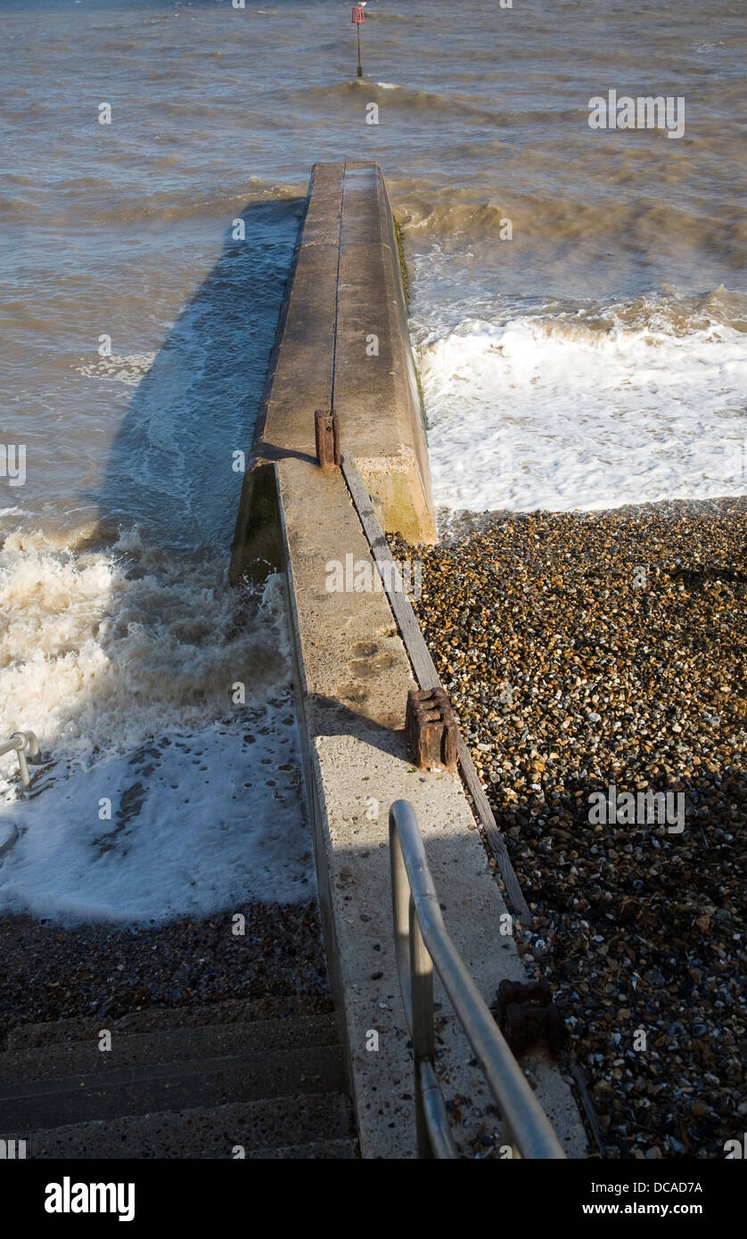 Beach sediment at differing levels either side of a concrete groyne due ...