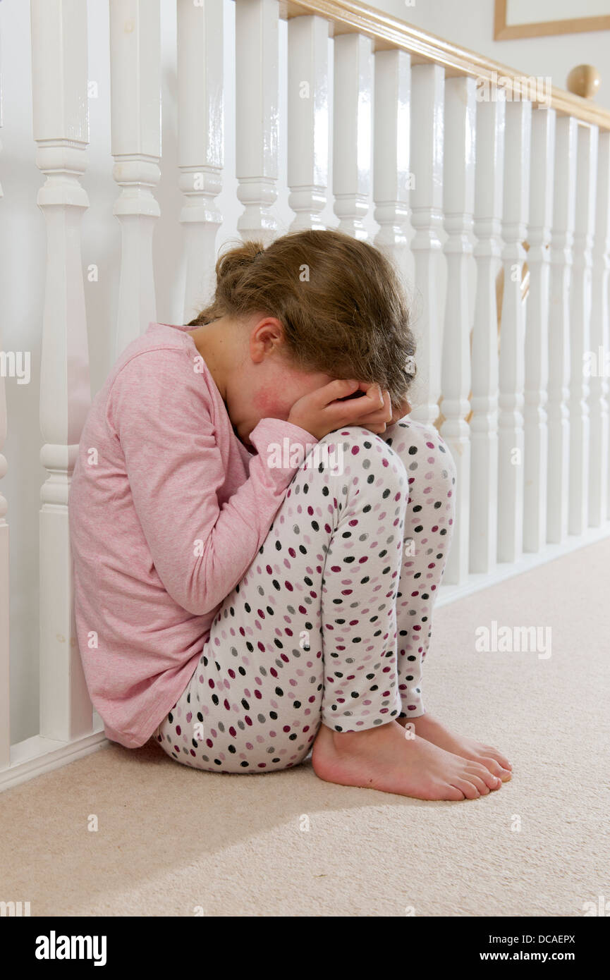 young girl upset sad and lonely holding head in hands crying huddled on ...