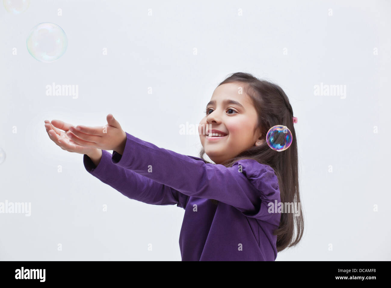 Young girl trying to catch a bubble Stock Photo - Alamy