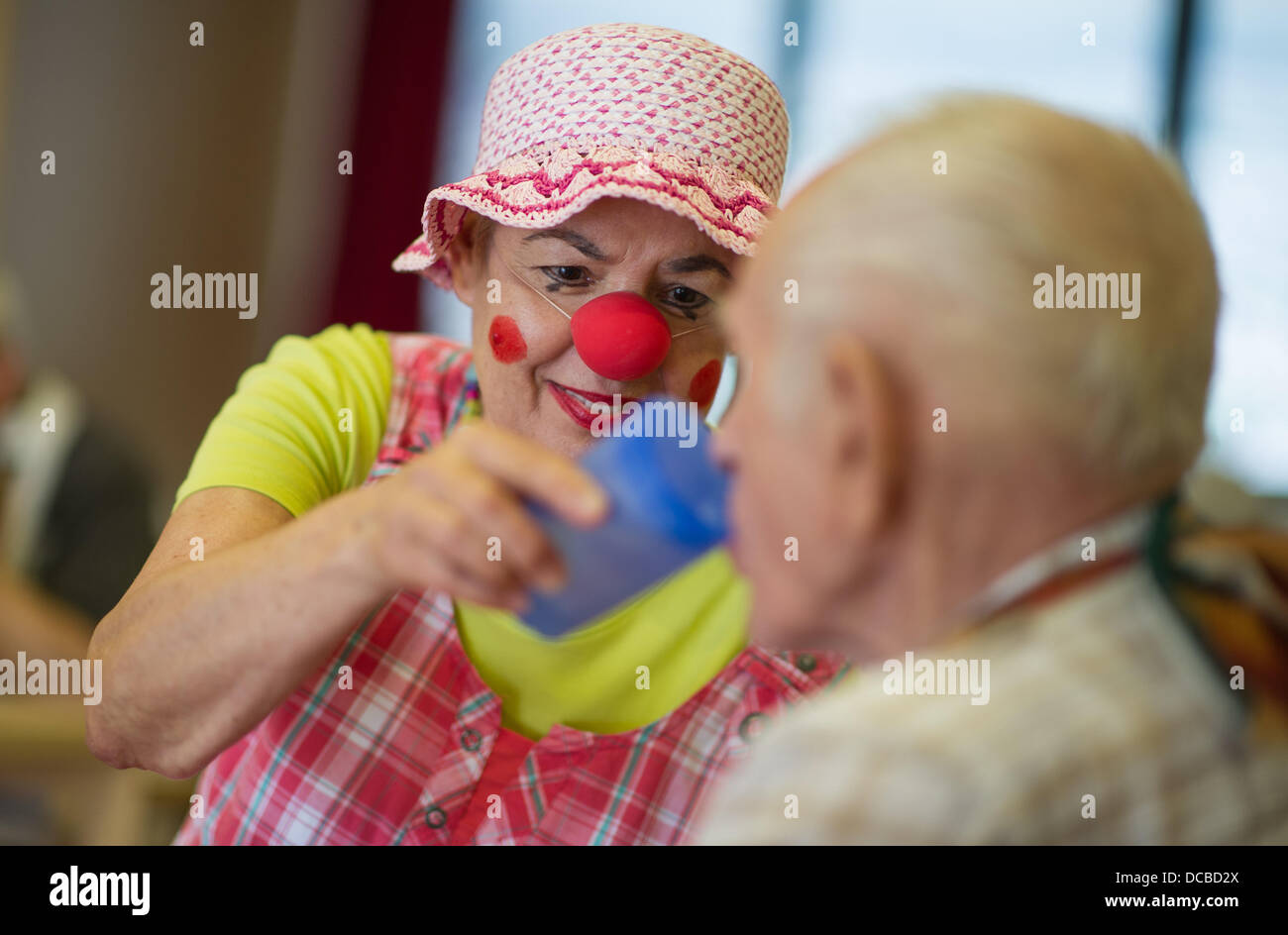 An employee in a clown's costume engages a dementia patient in the care ...