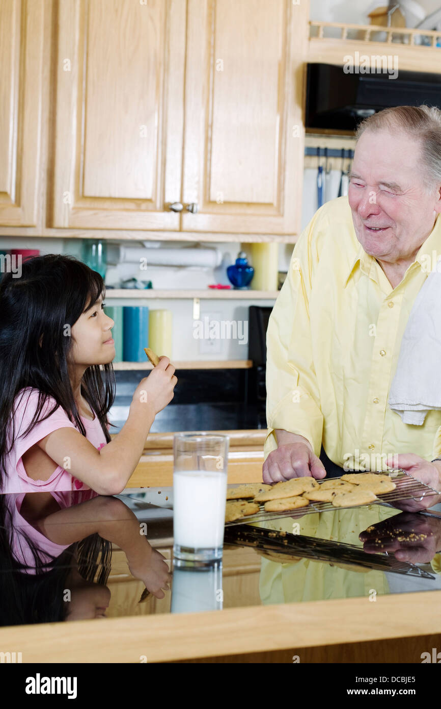 Elderly man sharing cookies with granddaughter Stock Photo - Alamy