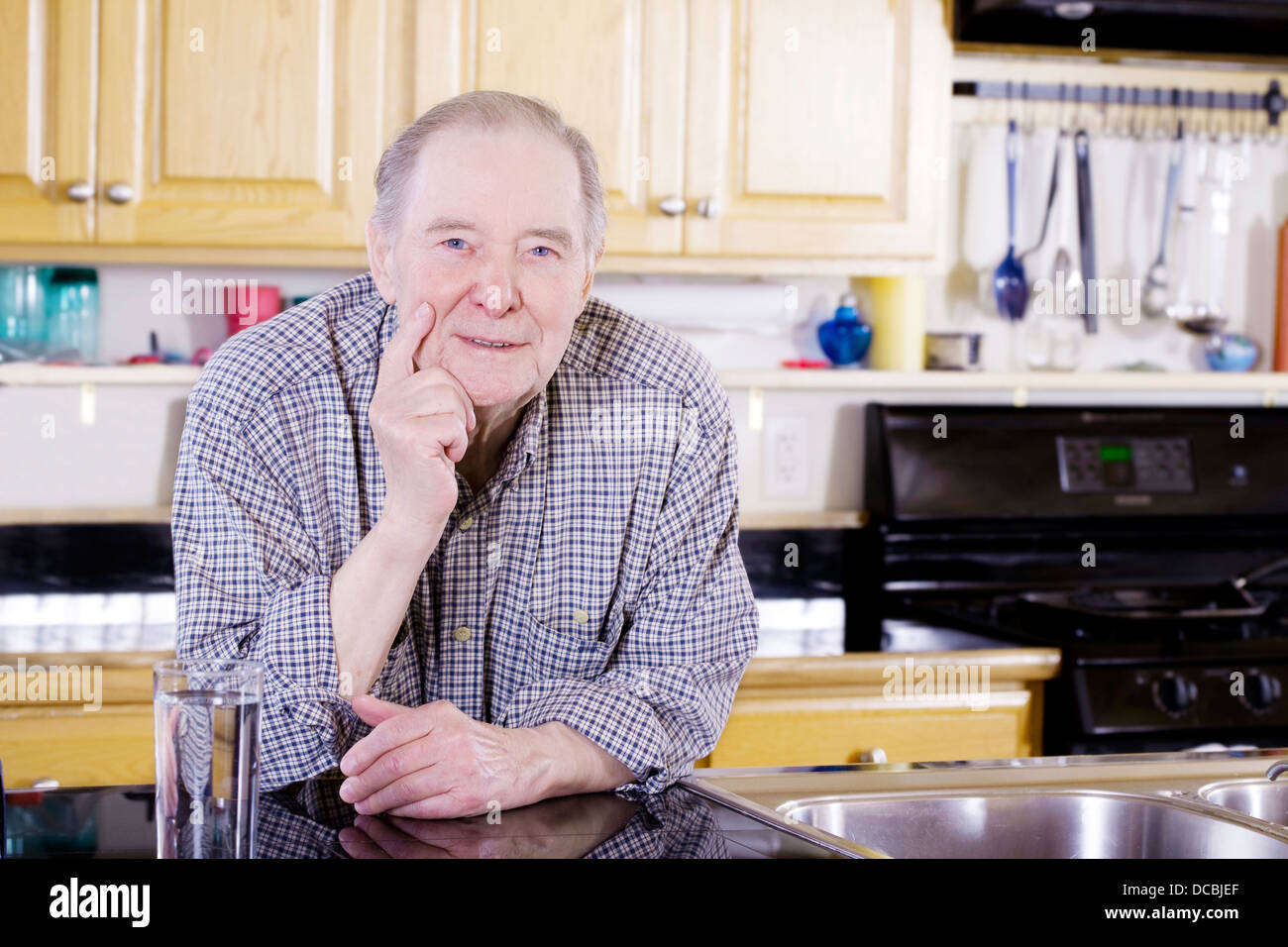 Elderly man leaning on counter Stock Photo - Alamy
