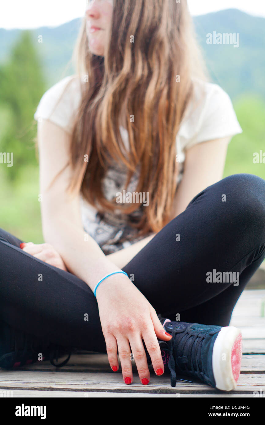 Teenager girl sitting on decking Stock Photo - Alamy