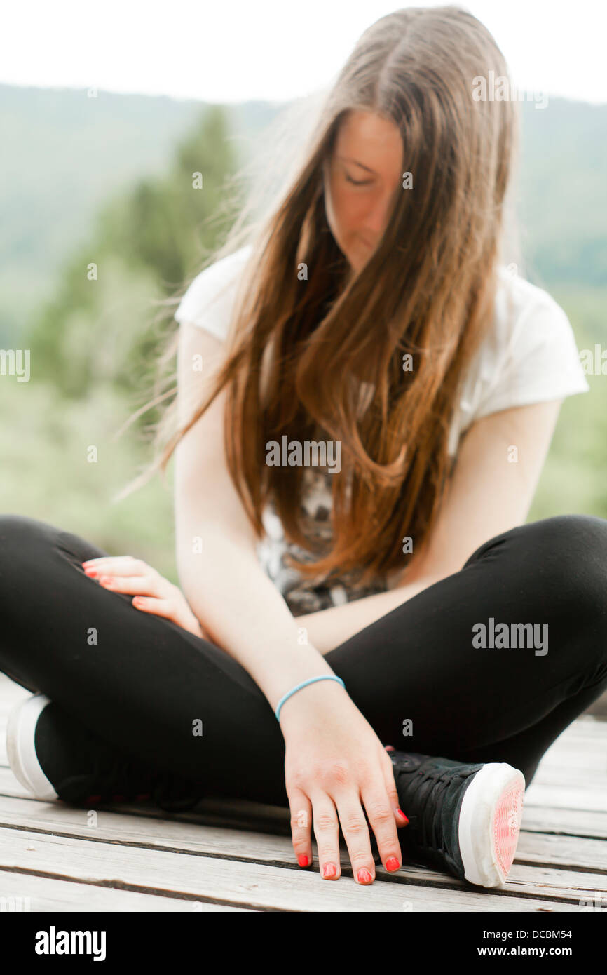 Teenager girl sitting on decking Stock Photo - Alamy