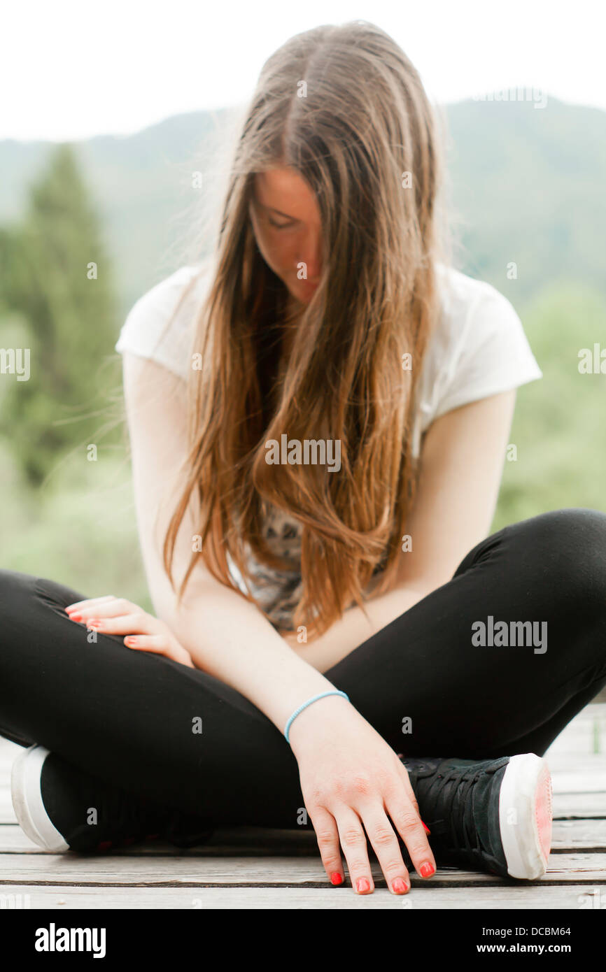 Teenager girl sitting on decking Stock Photo - Alamy