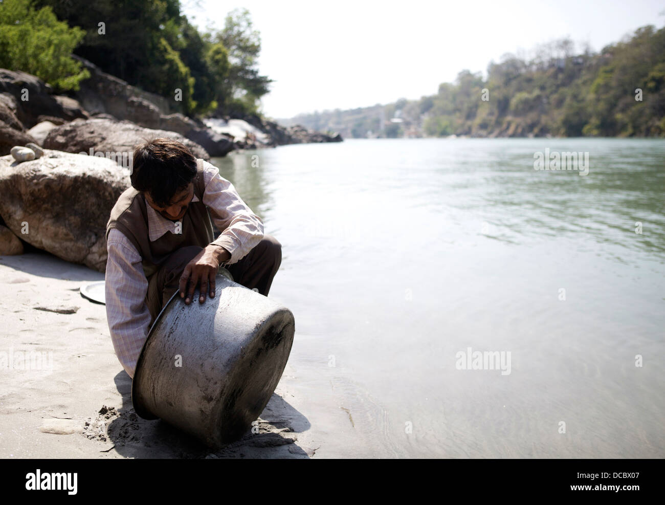An Indian man cleans a large cooking pot in the River Ganges in ...