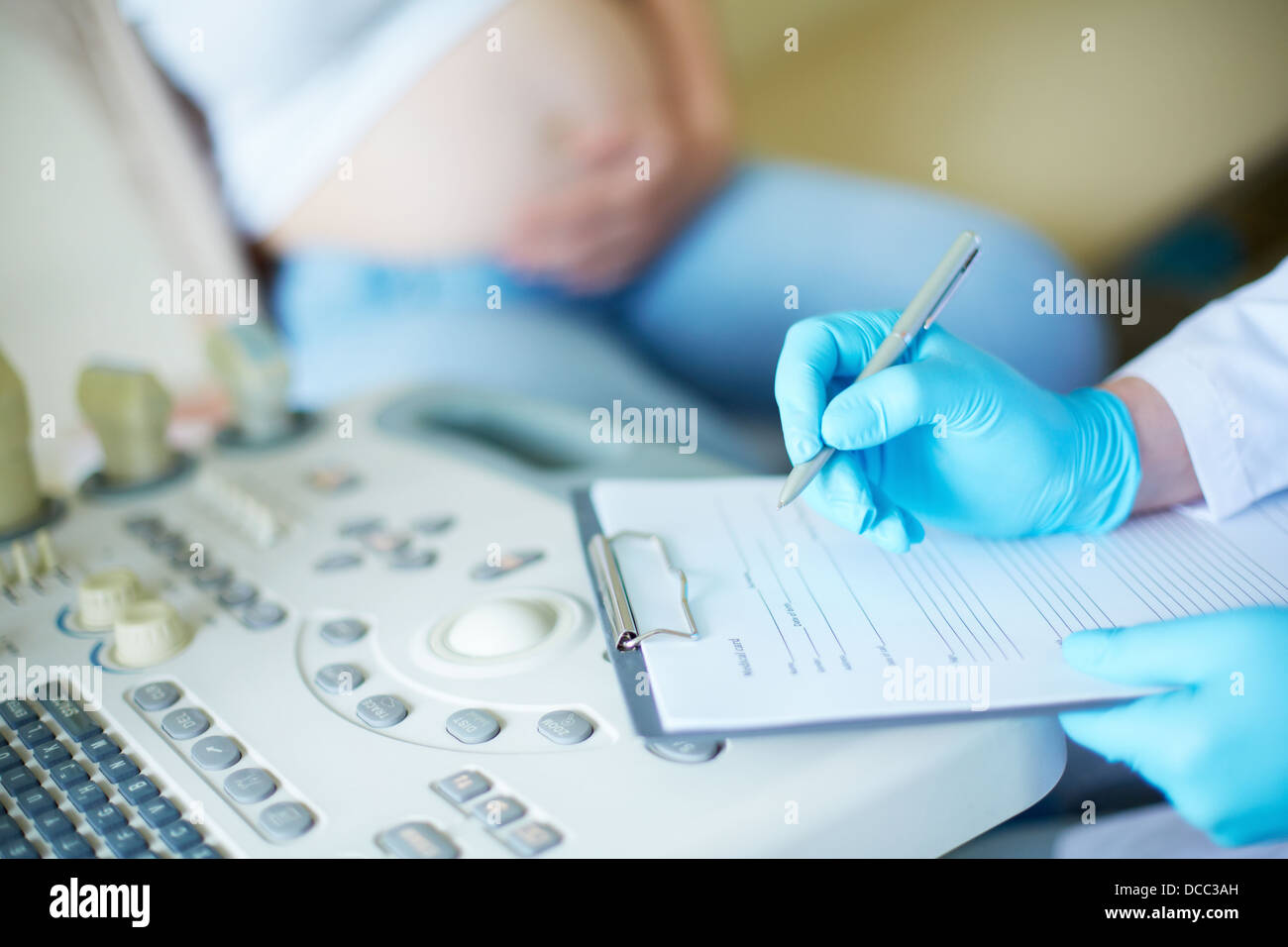 Gloved hand of obstetrician making notes during regular examination at ...