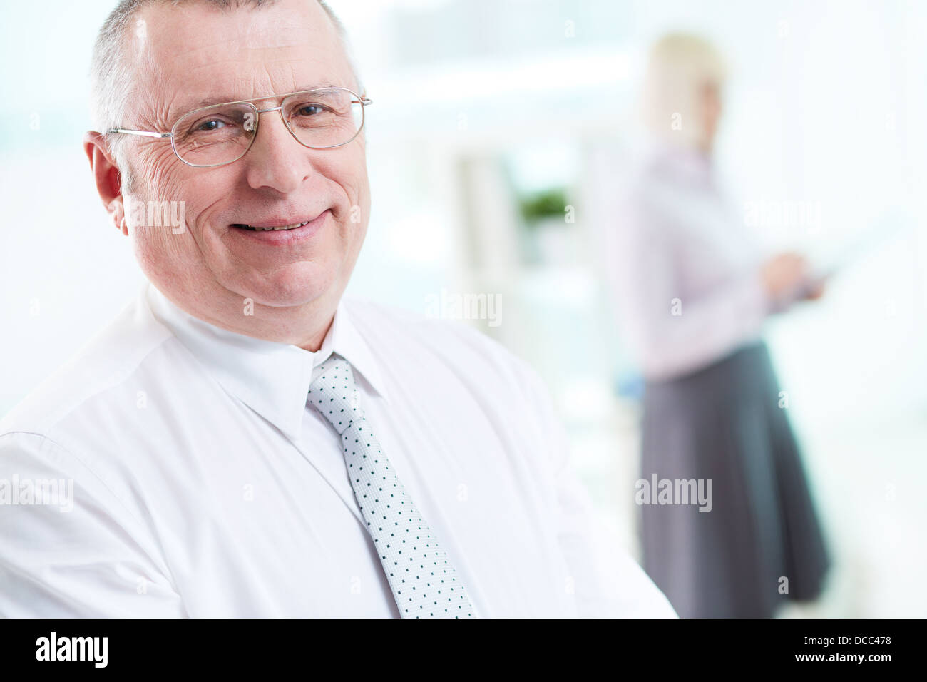 Portrait of smiling boss looking at camera with female standing on ...