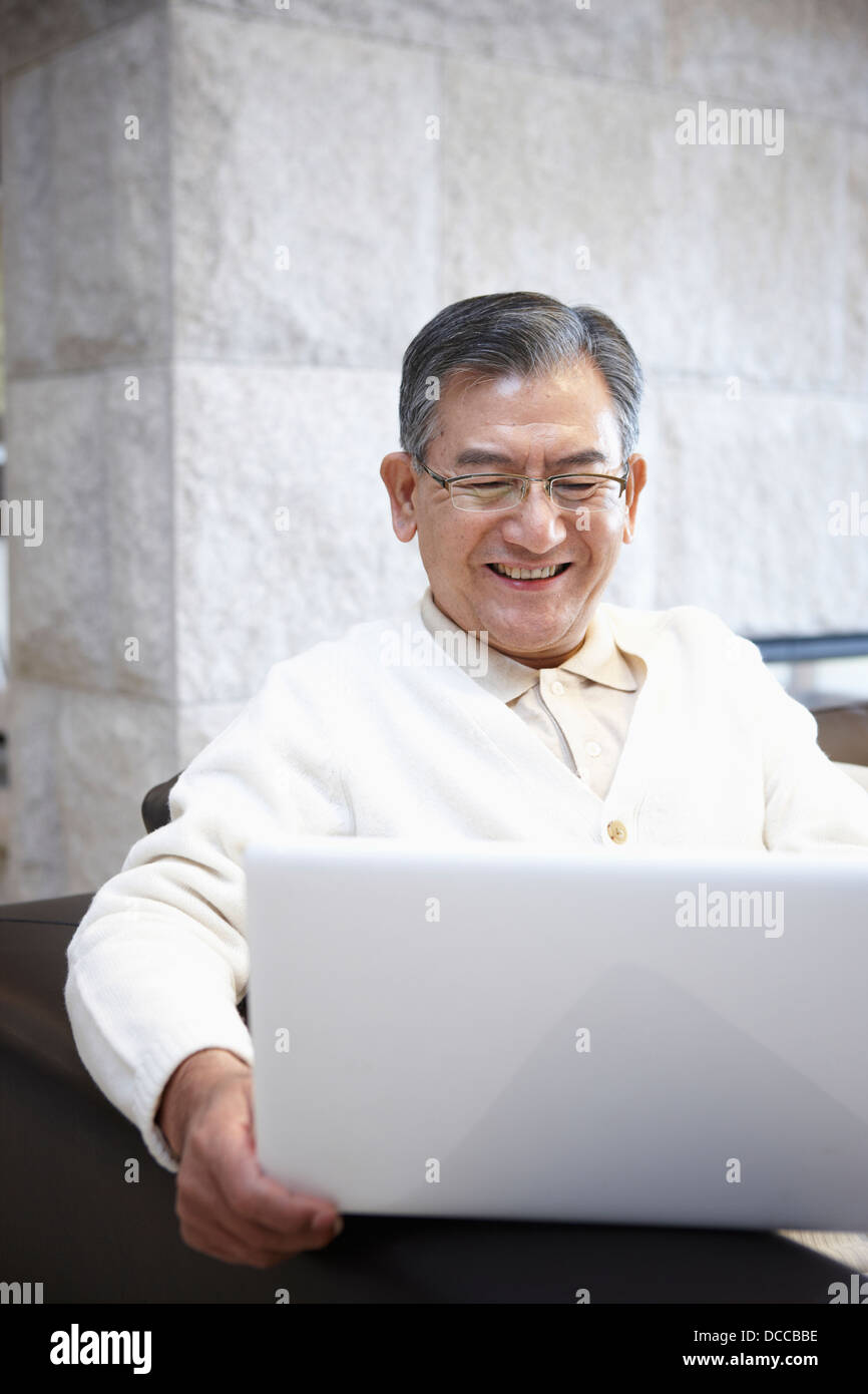 middle aged man sitting on a couch using a laptop Stock Photo - Alamy