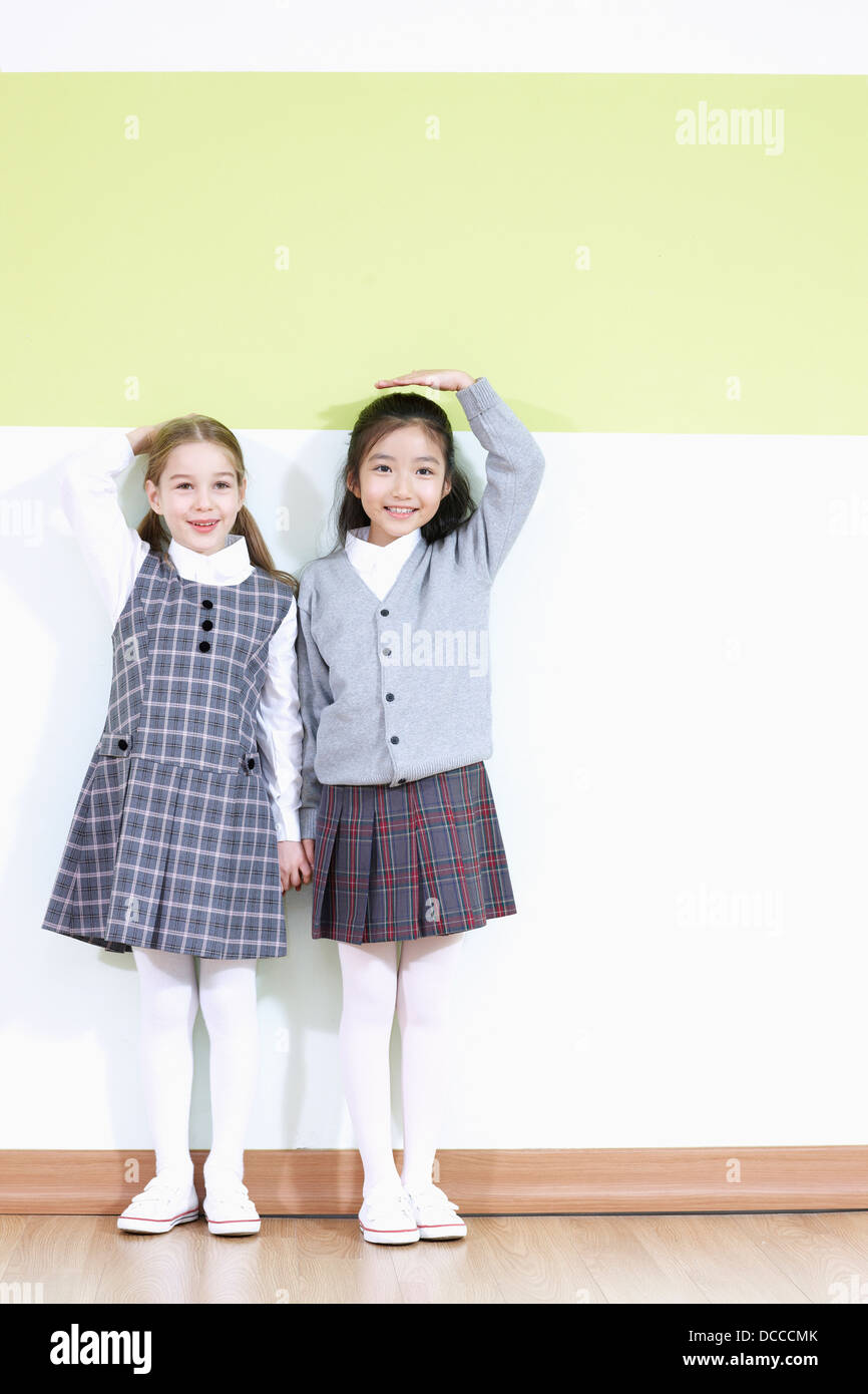 two girls measuring their heights in classroom Stock Photo - Alamy