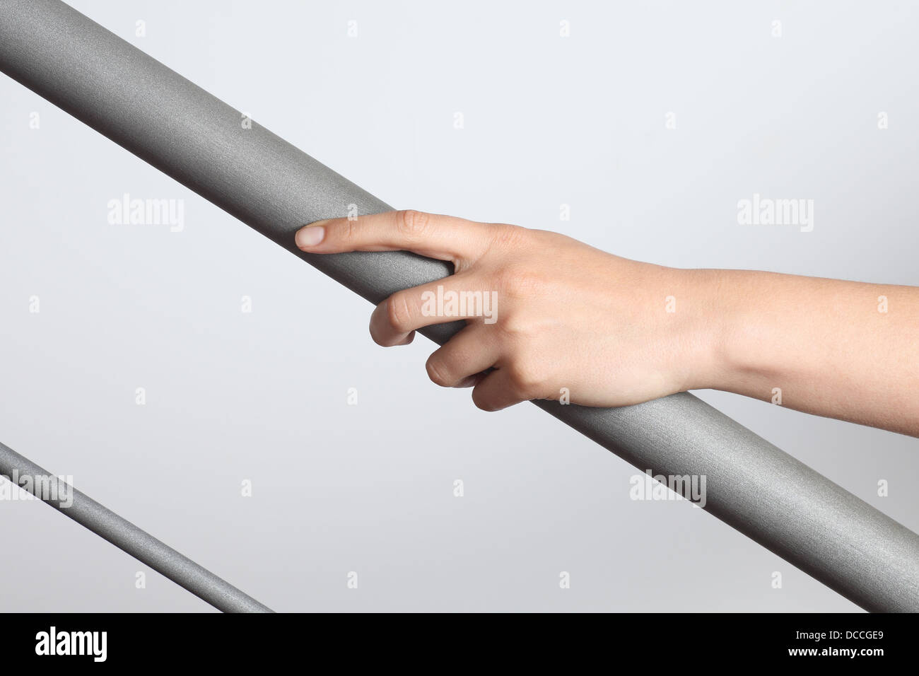 Woman hand using a railing to go upstairs with a light grey background ...