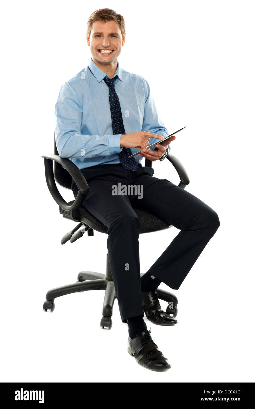 Corporate man sitting on chair and working on wireless touch pad device ...