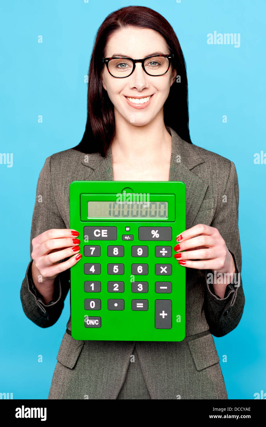 Happy young woman showing big green calculator against blue background ...