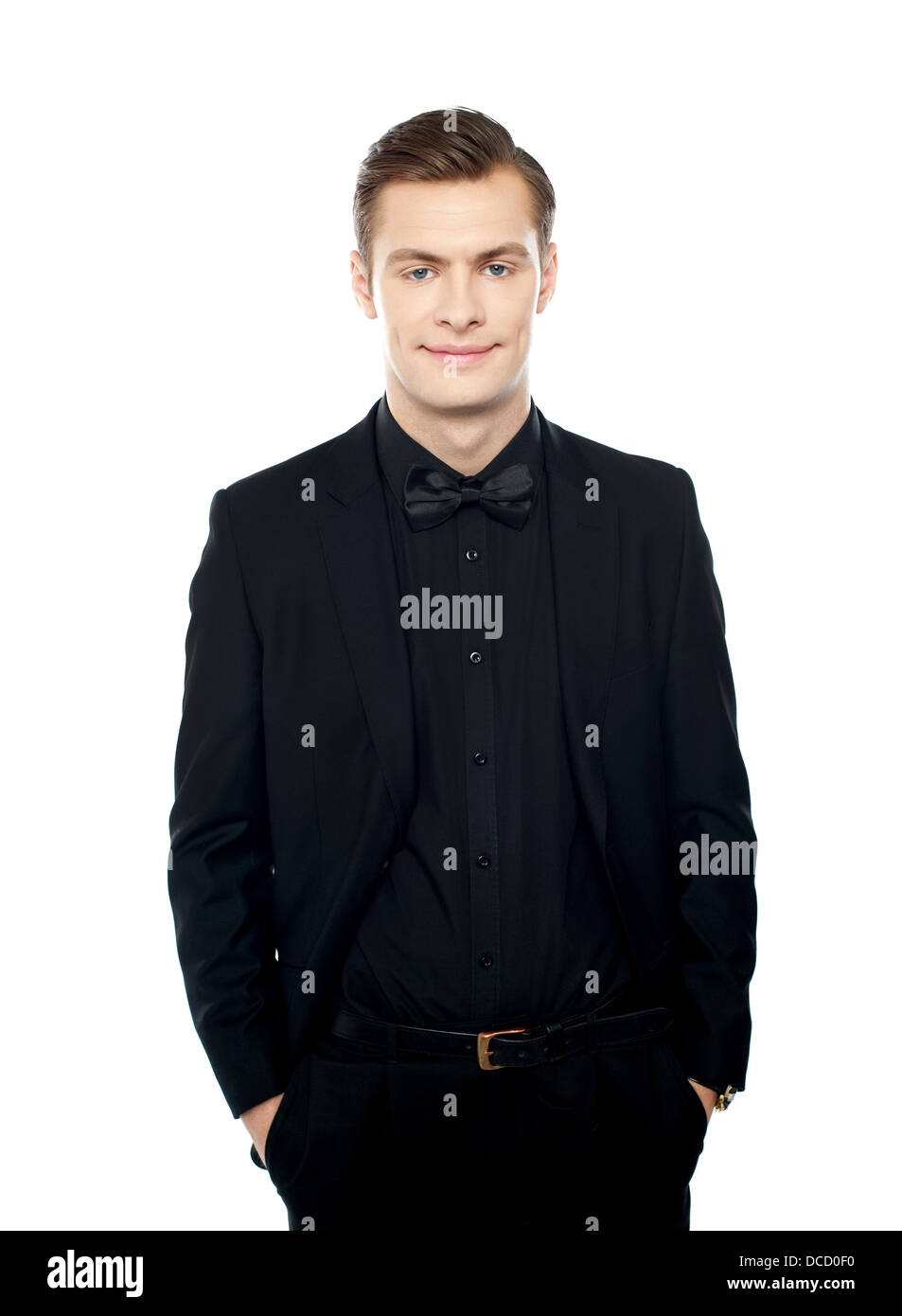 Elegant positive young guy posing with arms in pocket dressed in black ...
