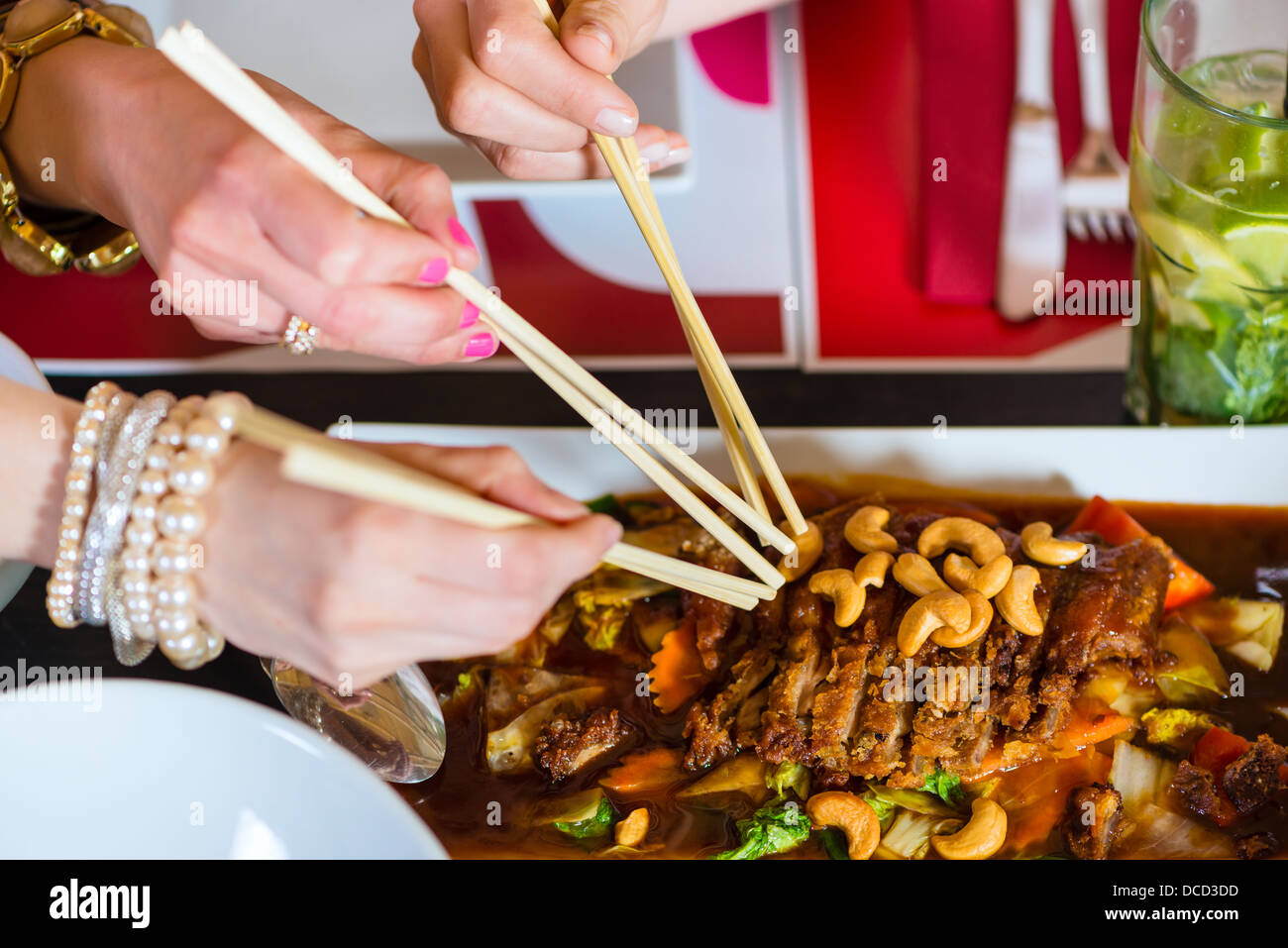 Young people eating in a Thai restaurant, they eating with chopsticks ...