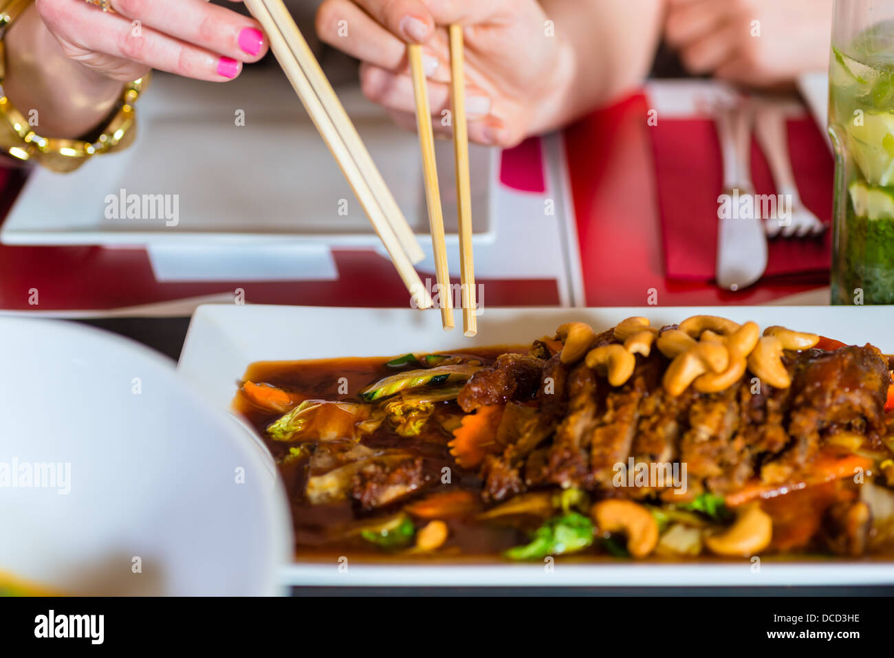 Young people eating in a Thai restaurant, they eating with chopsticks ...