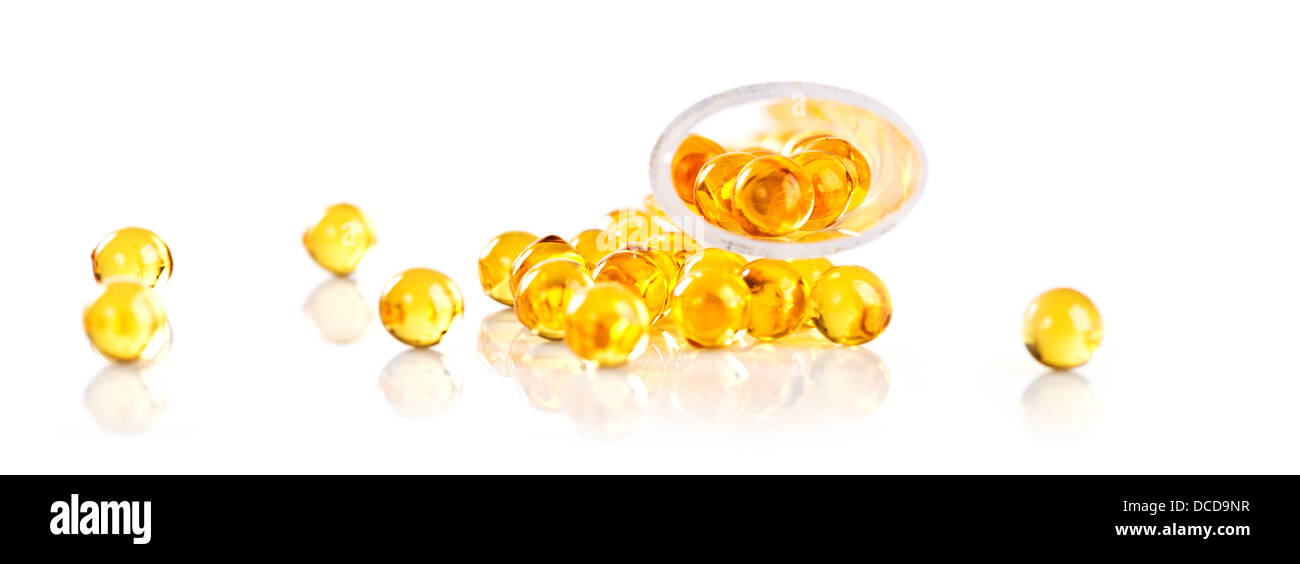 Capsules of fish oil spilled out open container Stock Photo - Alamy