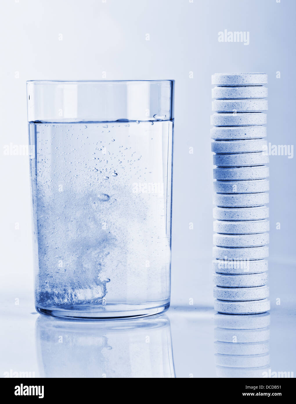 Fizzy tablet in a glass of water and stack of tablets Stock Photo - Alamy