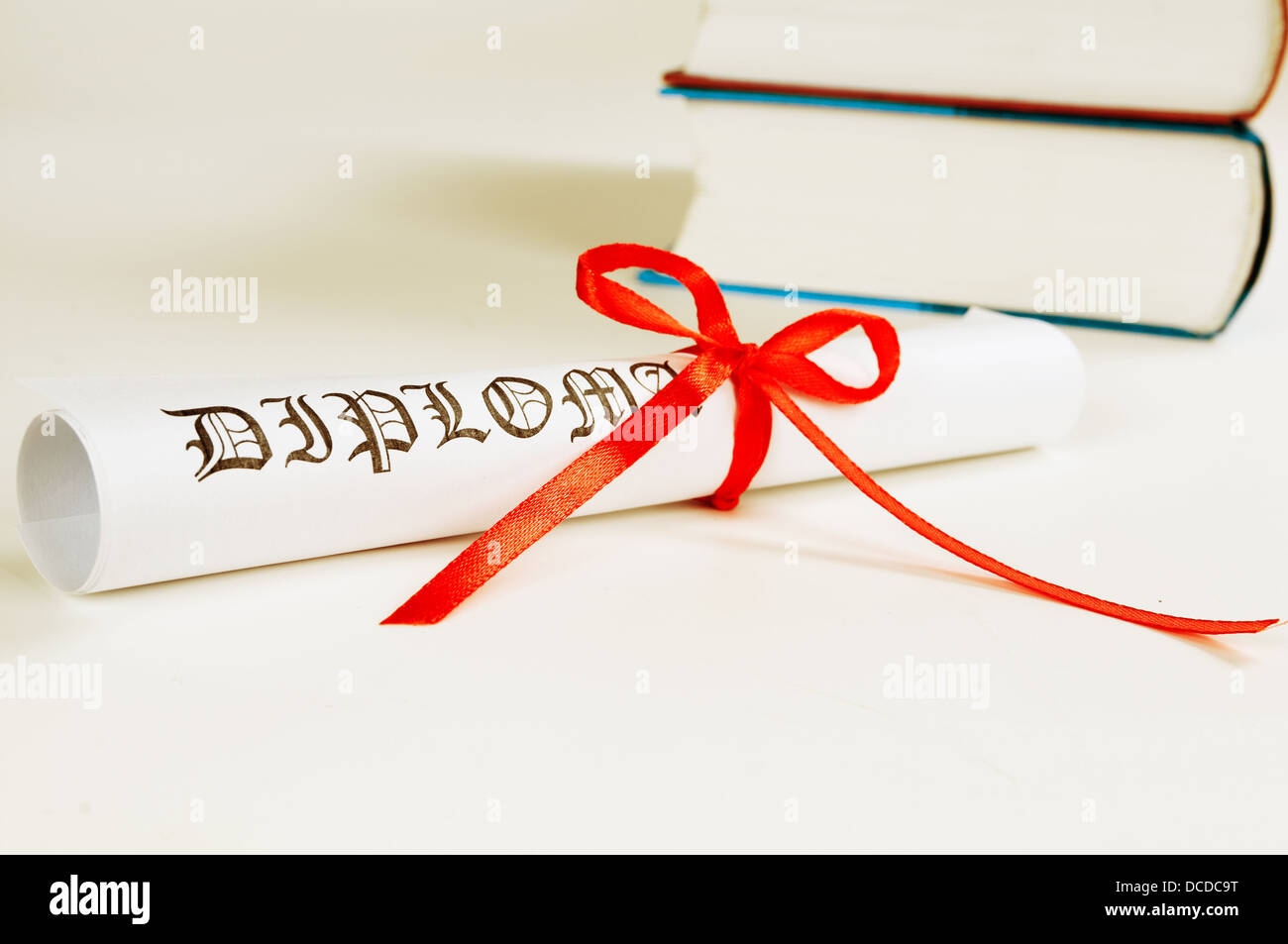 Diploma with red ribbon and books Stock Photo - Alamy