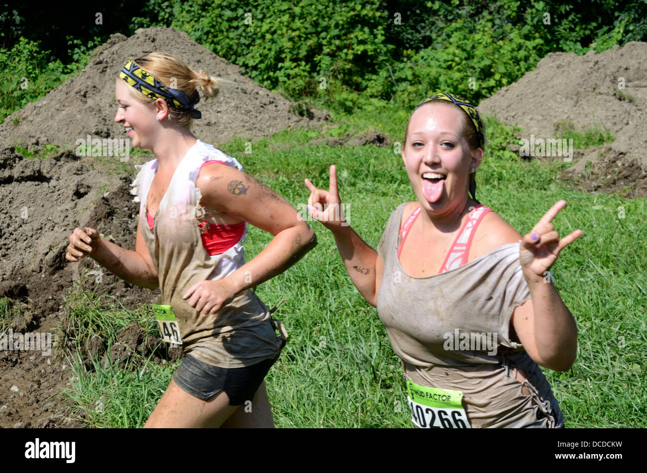 Happy young women waving to photographer in mud run race Stock Photo ...