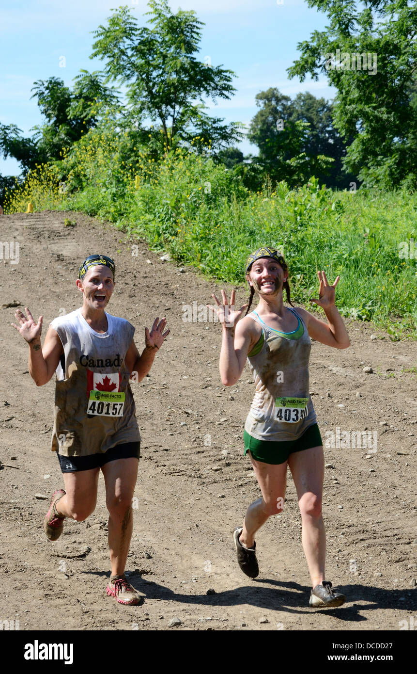 Happy young women waving to photographer in mud run race Stock Photo ...