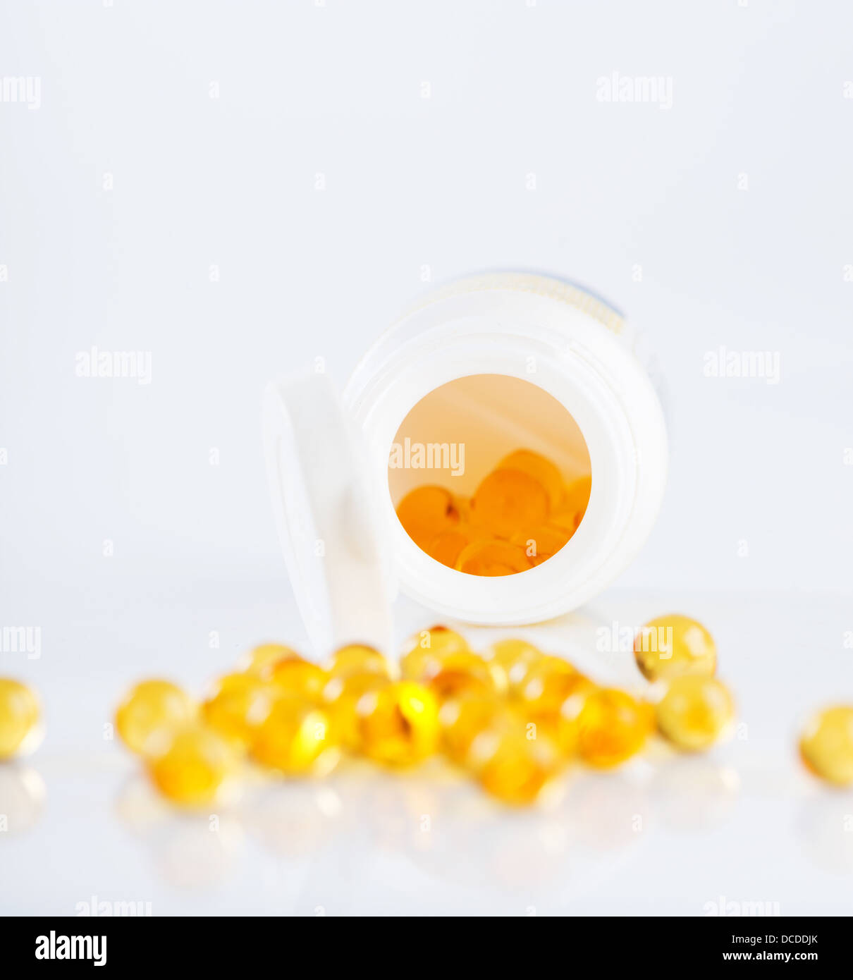 Capsules of fish oil spilled out open container Stock Photo - Alamy