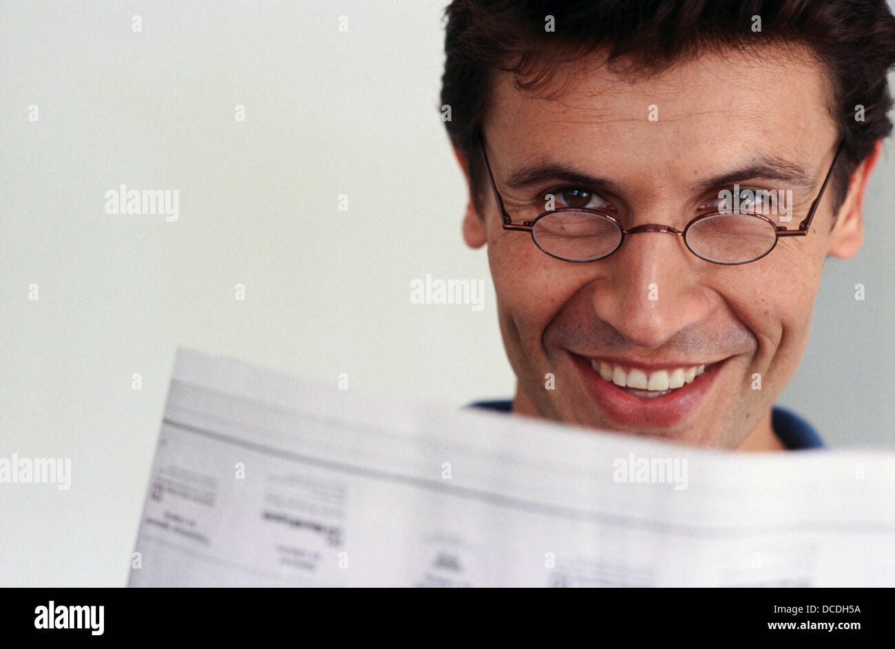 Smiling man looking over his newspaper Stock Photo - Alamy