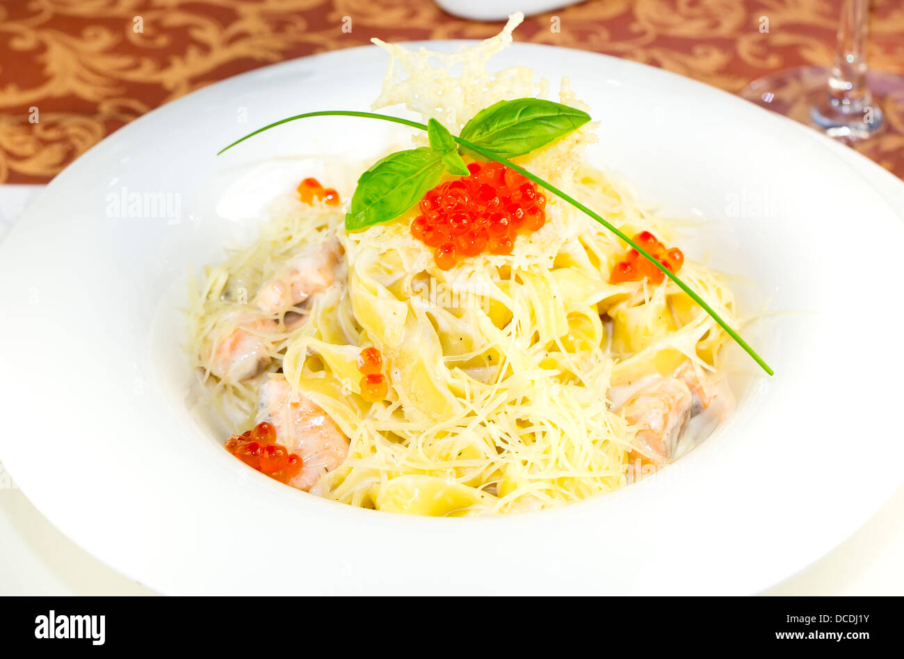 Pasta with fish red caviar and cheese on the table in a restaurant ...