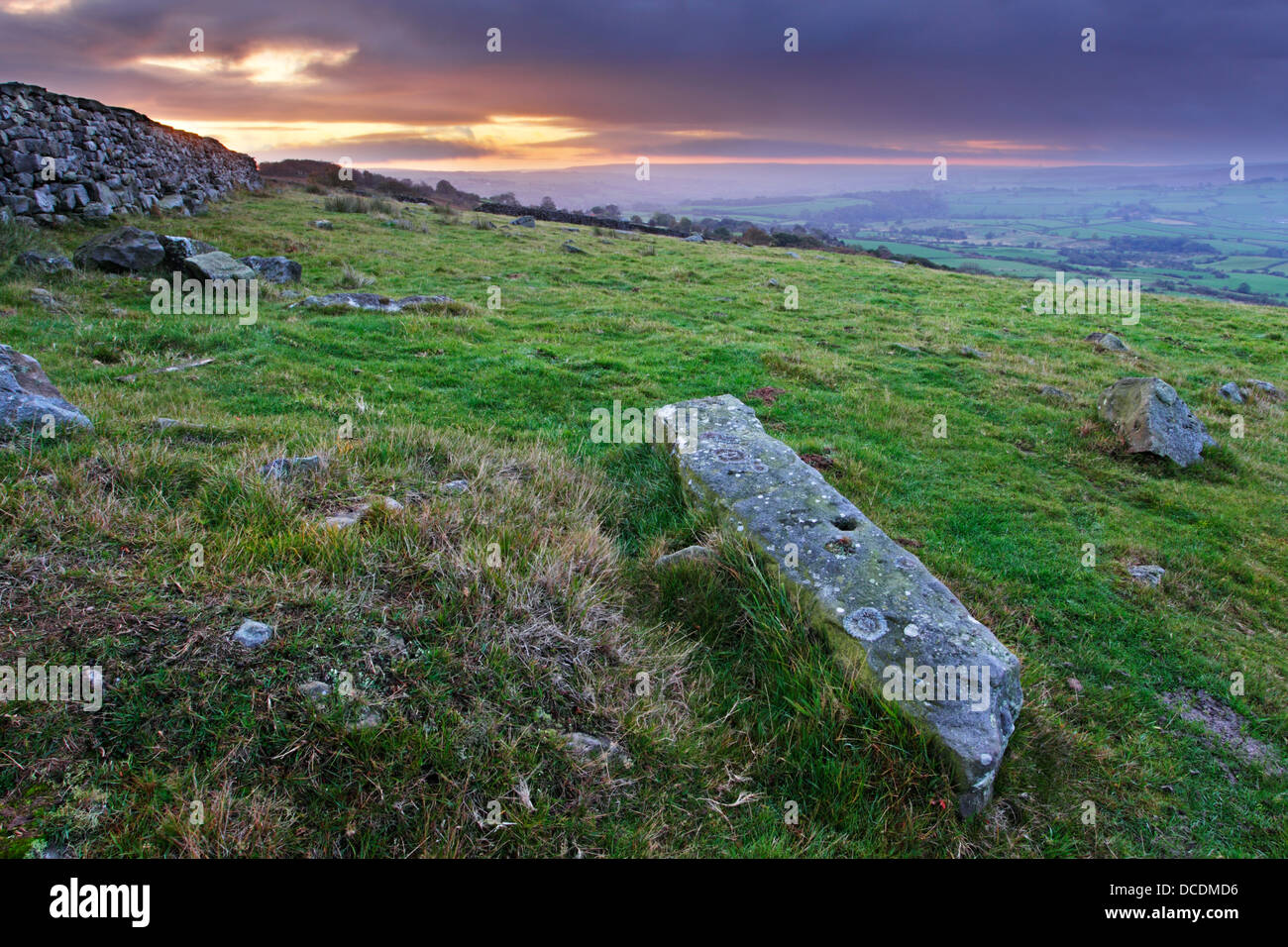 An old stone gatepost lies abandoned under a brooding sky in a field ...