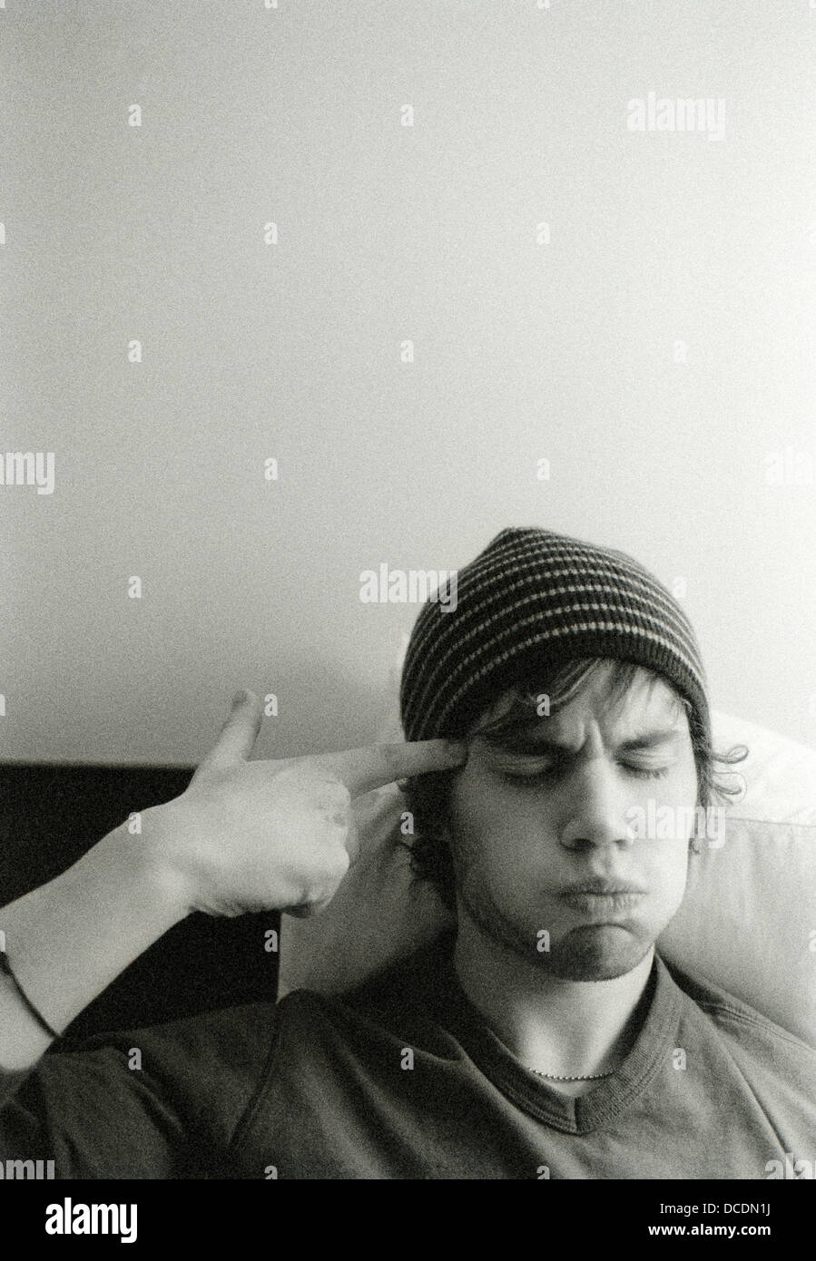 young man with finger pointing at his head, eyes closed Stock Photo - Alamy