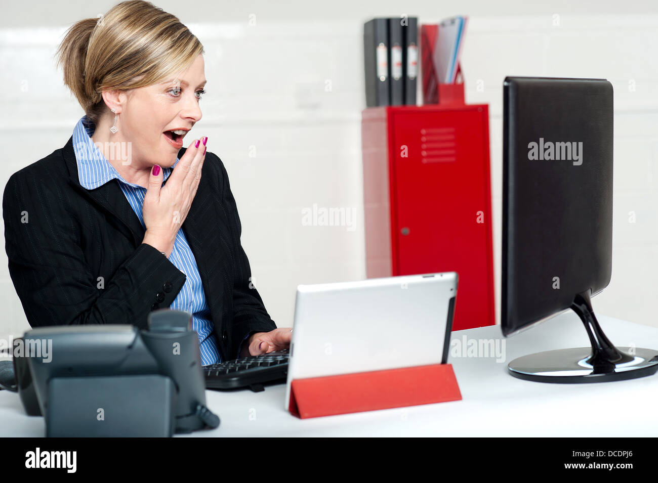 Surprised female secretary looking at lcd screen. Indoors office shot ...
