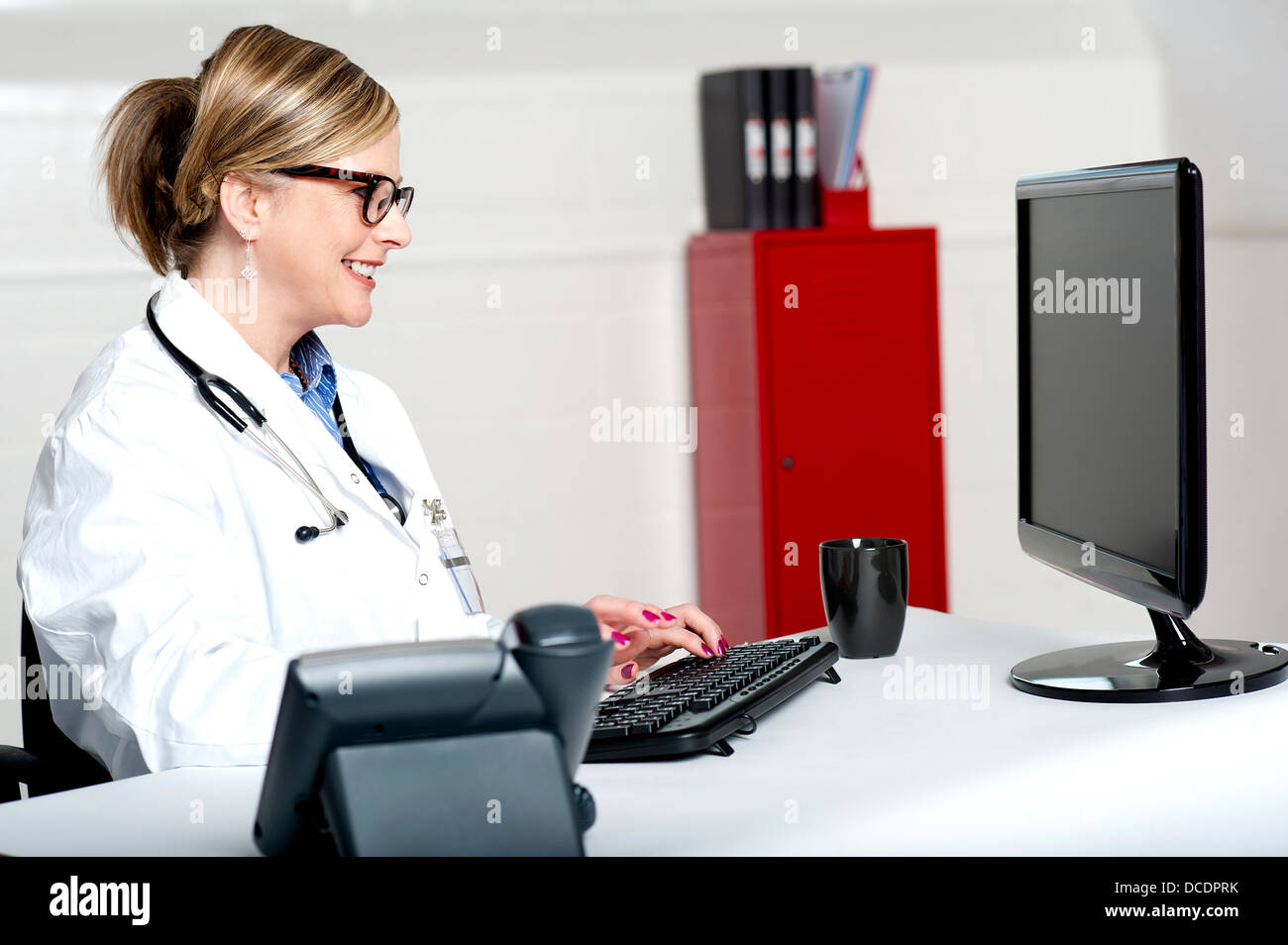 Experienced physician typing medical report Stock Photo - Alamy
