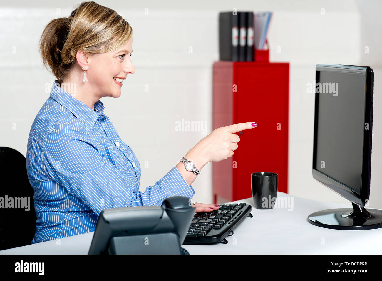 Businesswoman pointing at computer screen seated in office Stock Photo ...
