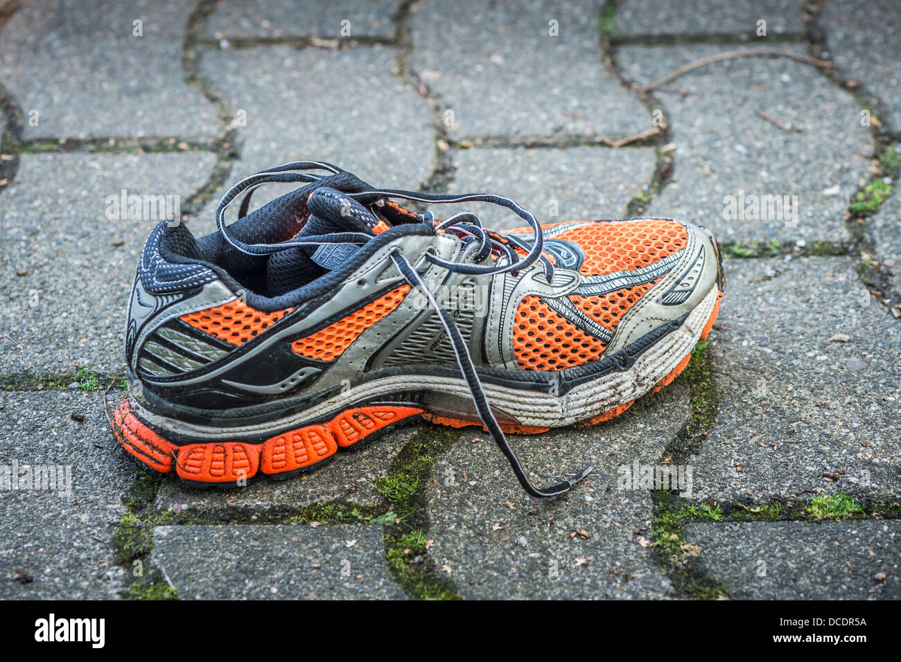 Single Orange Training Shoe on Paving Stock Photo - Alamy
