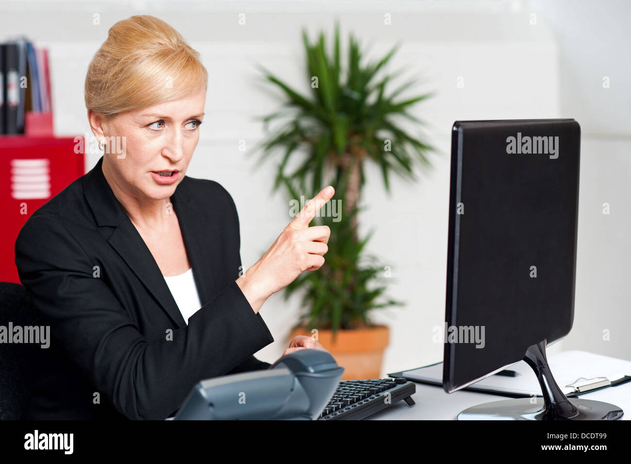 Angry woman in office indicating at computer led screen Stock Photo - Alamy