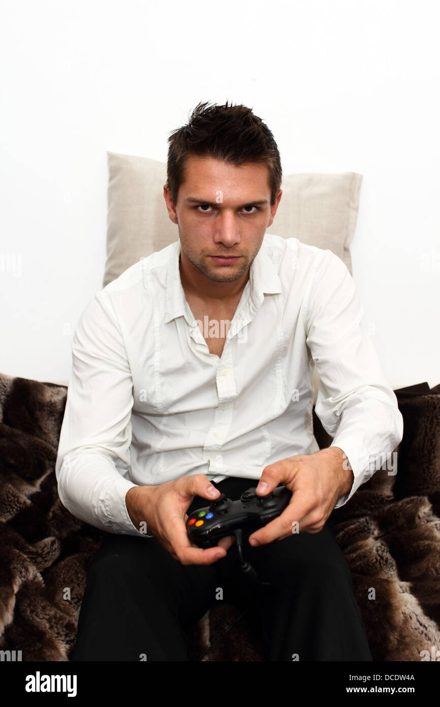 Gamer sitting on couch with controller and playing Stock Photo - Alamy