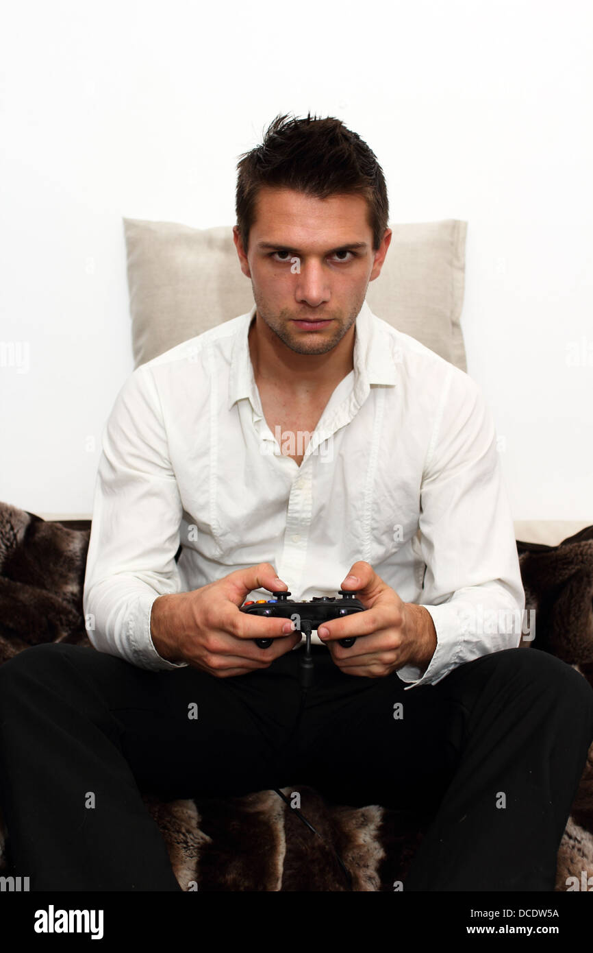 Gamer sitting on couch with controller and playing Stock Photo - Alamy