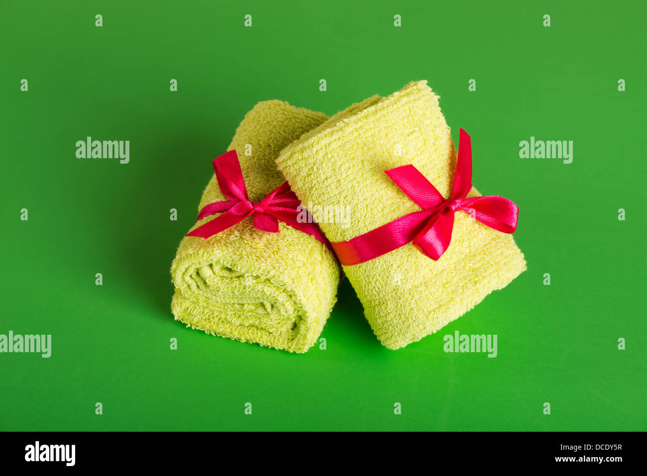 rolled up green beach towel on green background Stock Photo - Alamy