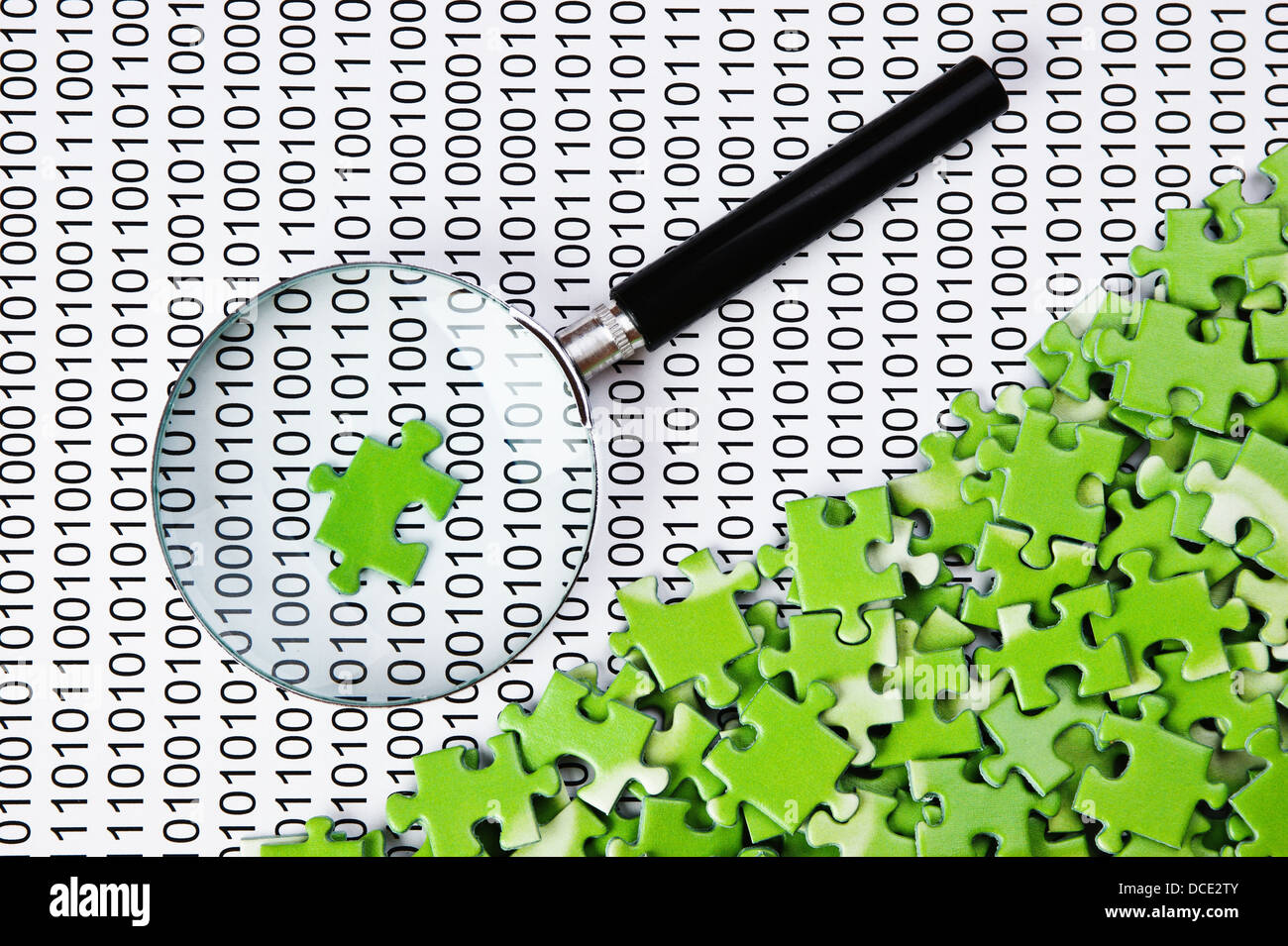 puzzles and magnifying glass on a binary code Stock Photo - Alamy