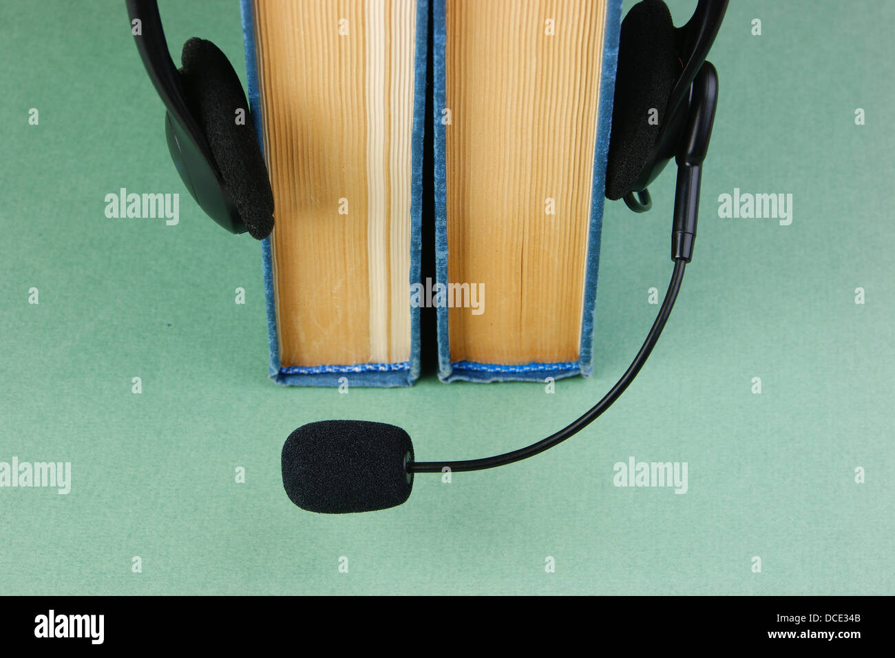 Headphones with a microphone and a stack of books on a green background ...