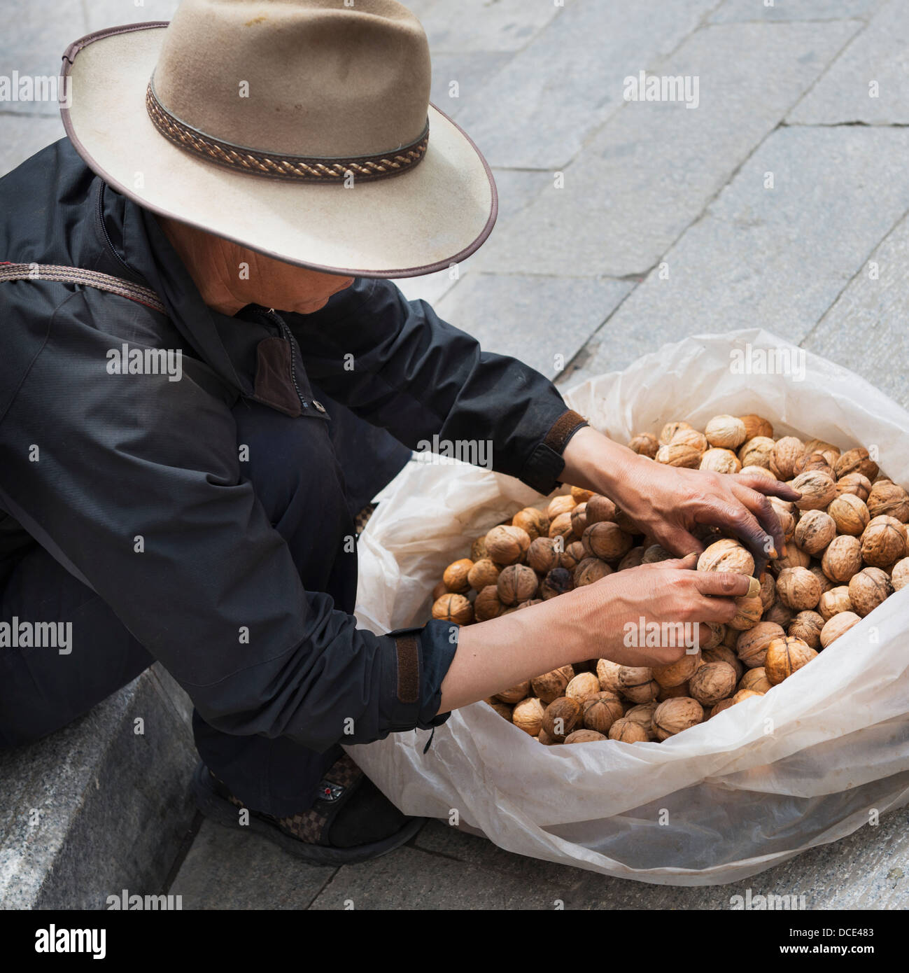 Man Sitting on Curb of Street Sorting Nuts in Bag; Tibet, Xizang, China ...