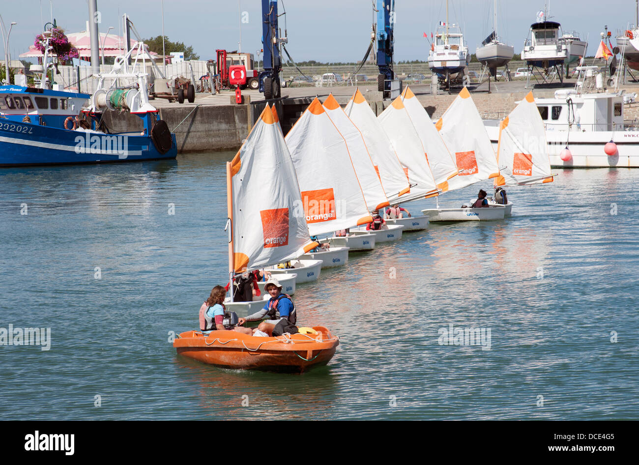 Optimist class sailing boats being towed accross the harbour in Saint ...