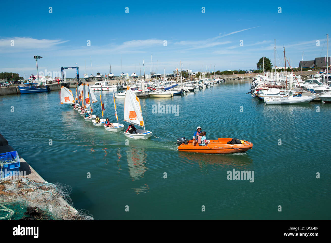 Optimist class sailing boats being towed accross the harbour in Saint ...